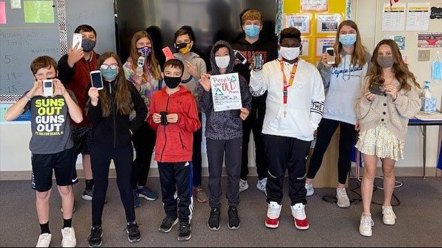 Image of group of students holding up old cell phones