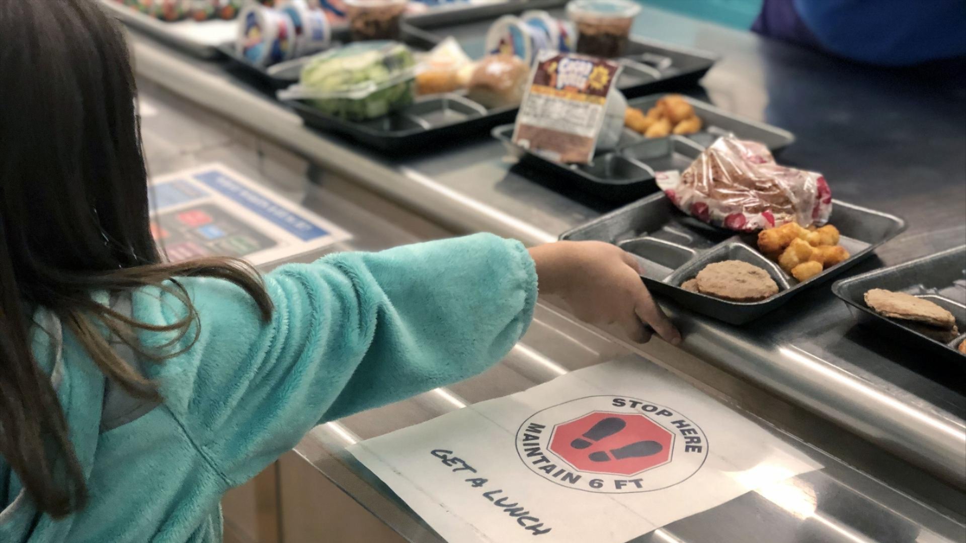 Image of student picking up lunch tray in cafeteria serving line