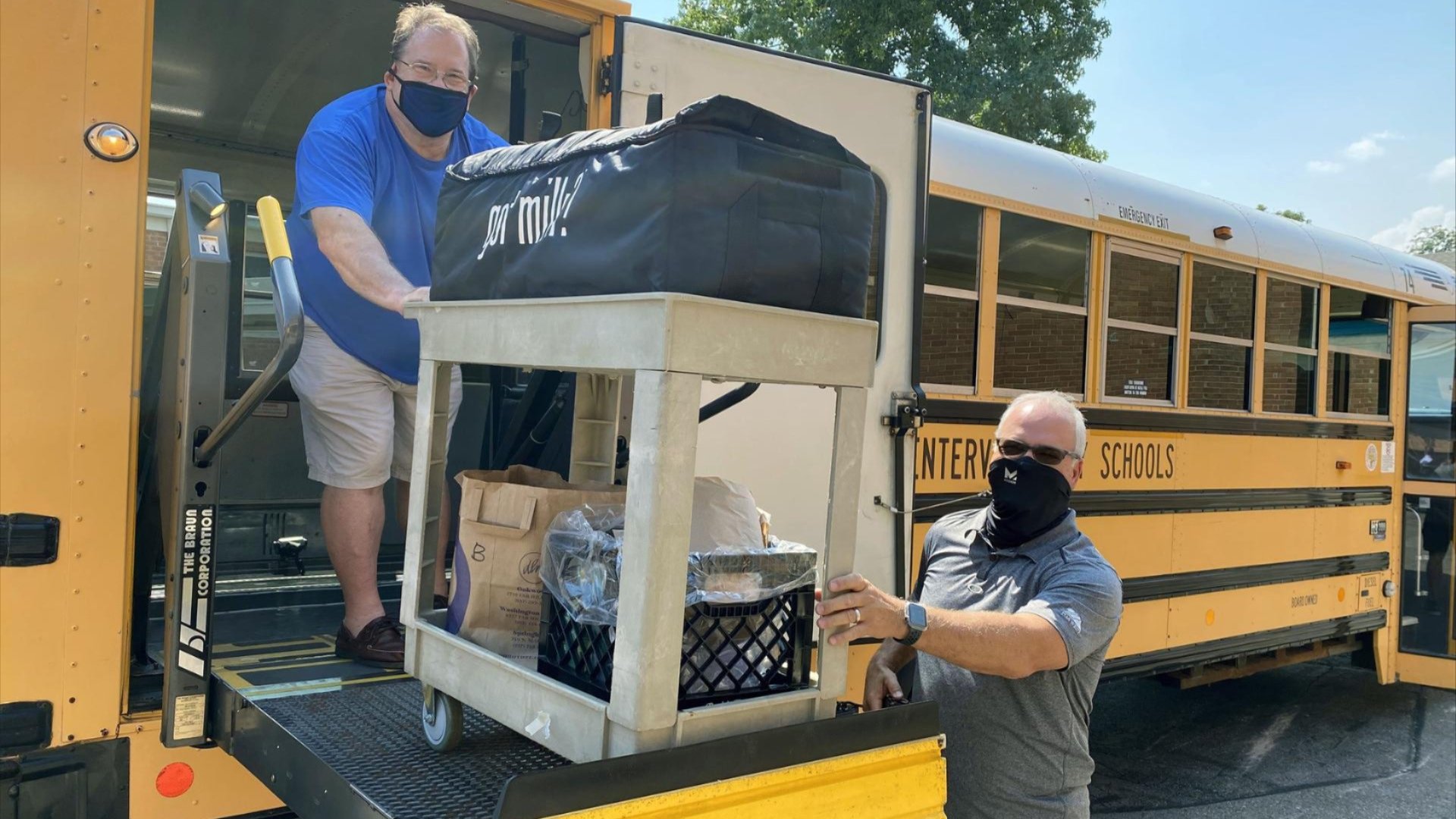 Image of two men loading food onto school bus